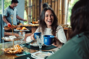 Uma área de refeições com uma mesa posta para dois, incluindo pratos, copos e uma caneca azul.