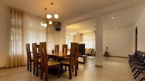 Uma área de refeições com mesa e cadeiras de madeira, televisão e um violão.
