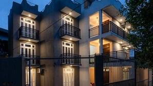 Um edifício residencial com vários andares, varandas, portão e entrada para carros.