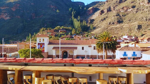 Um banco de madeira com bancos num pátio com vista para uma aldeia no topo da colina.