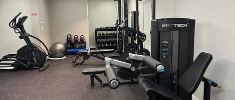 Uma academia com equipamentos de cardio, aparelhos de musculação e pesos livres.