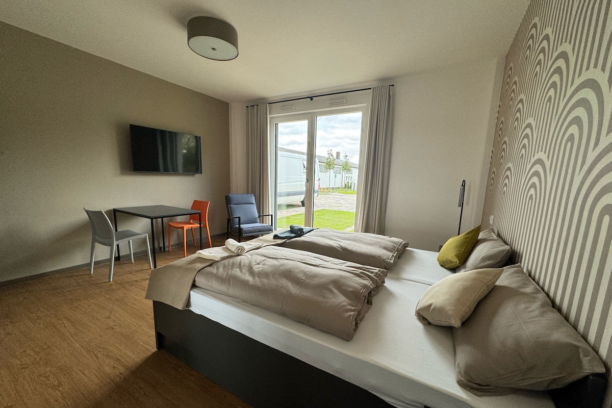 Quarto de hotel moderno com uma cama grande, uma escrivaninha e uma televisão.