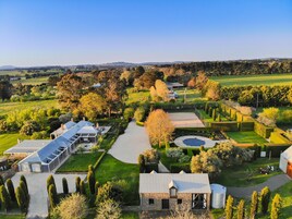 Uma grande propriedade com vários edifícios, um jardim bem cuidado e uma vista panorâmica do campo circundante.