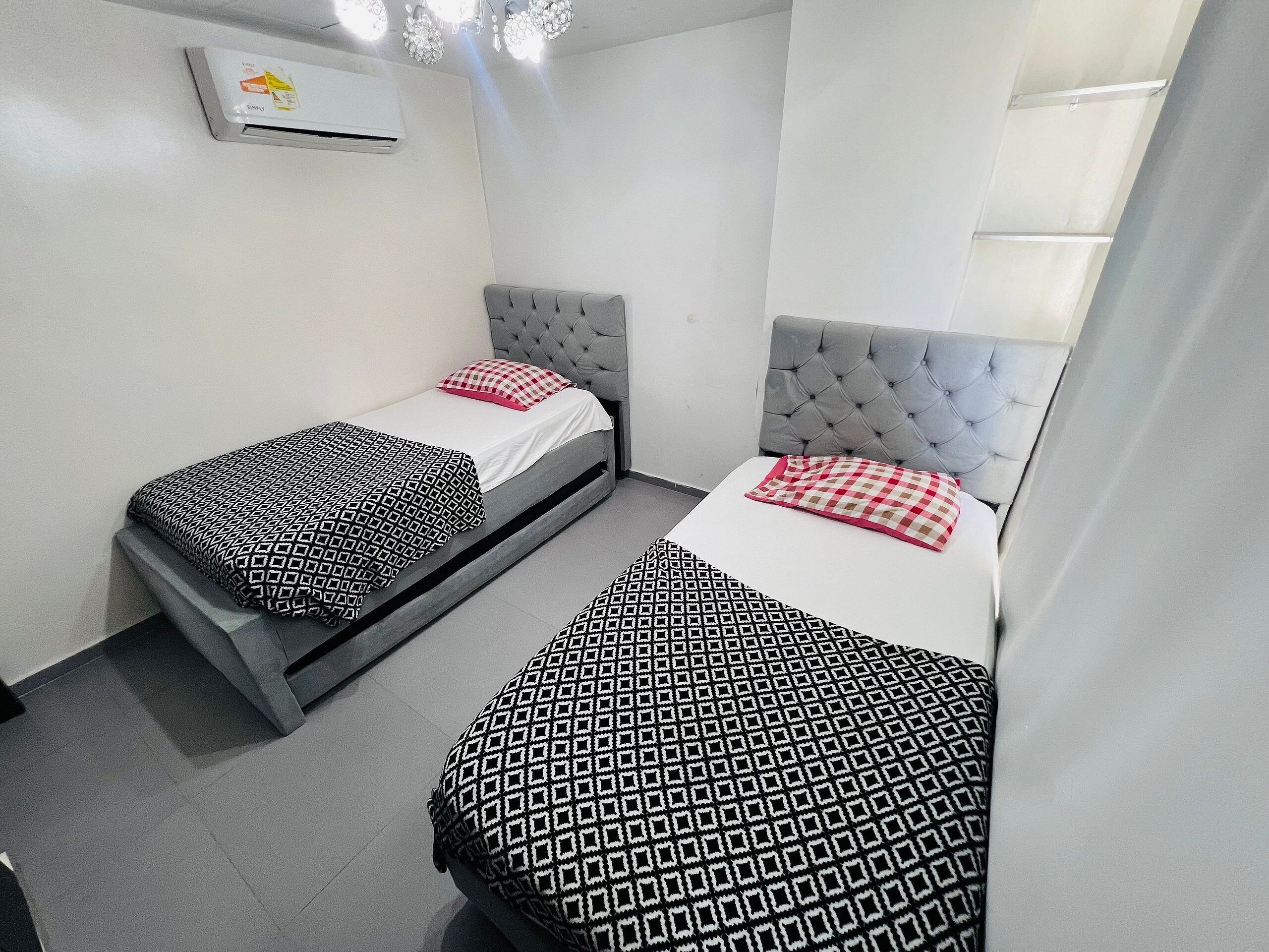 Quarto com duas camas, cada uma com colcha estampada e cabeceira acolchoada.