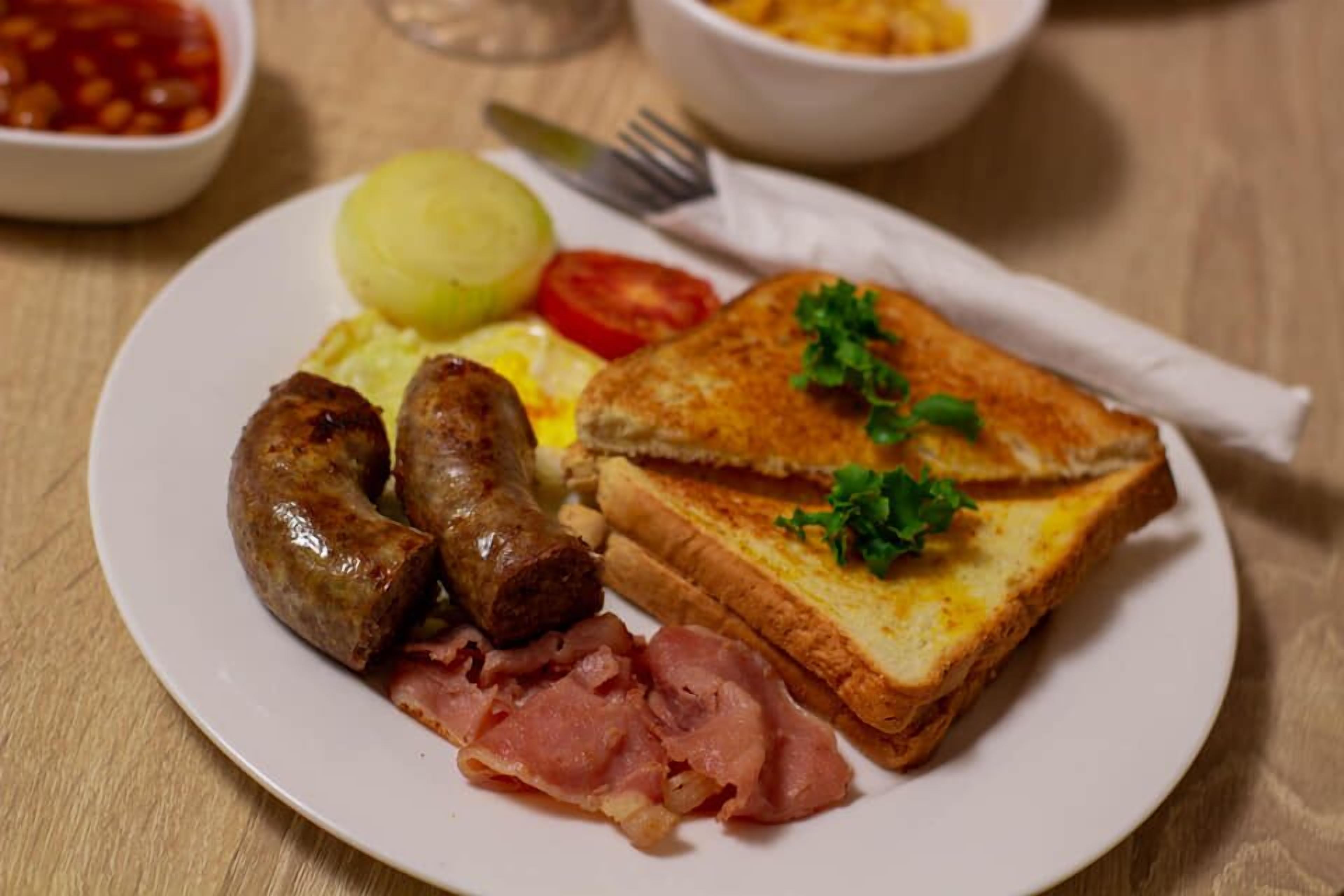 Um prato com torradas, salsichas, fiambre e ovo cozido.