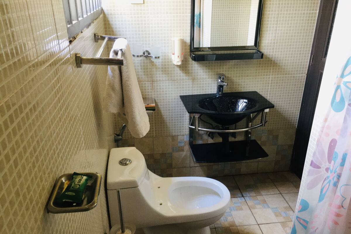 Casa de banho com sanita, lavatório e porta-toalhas.