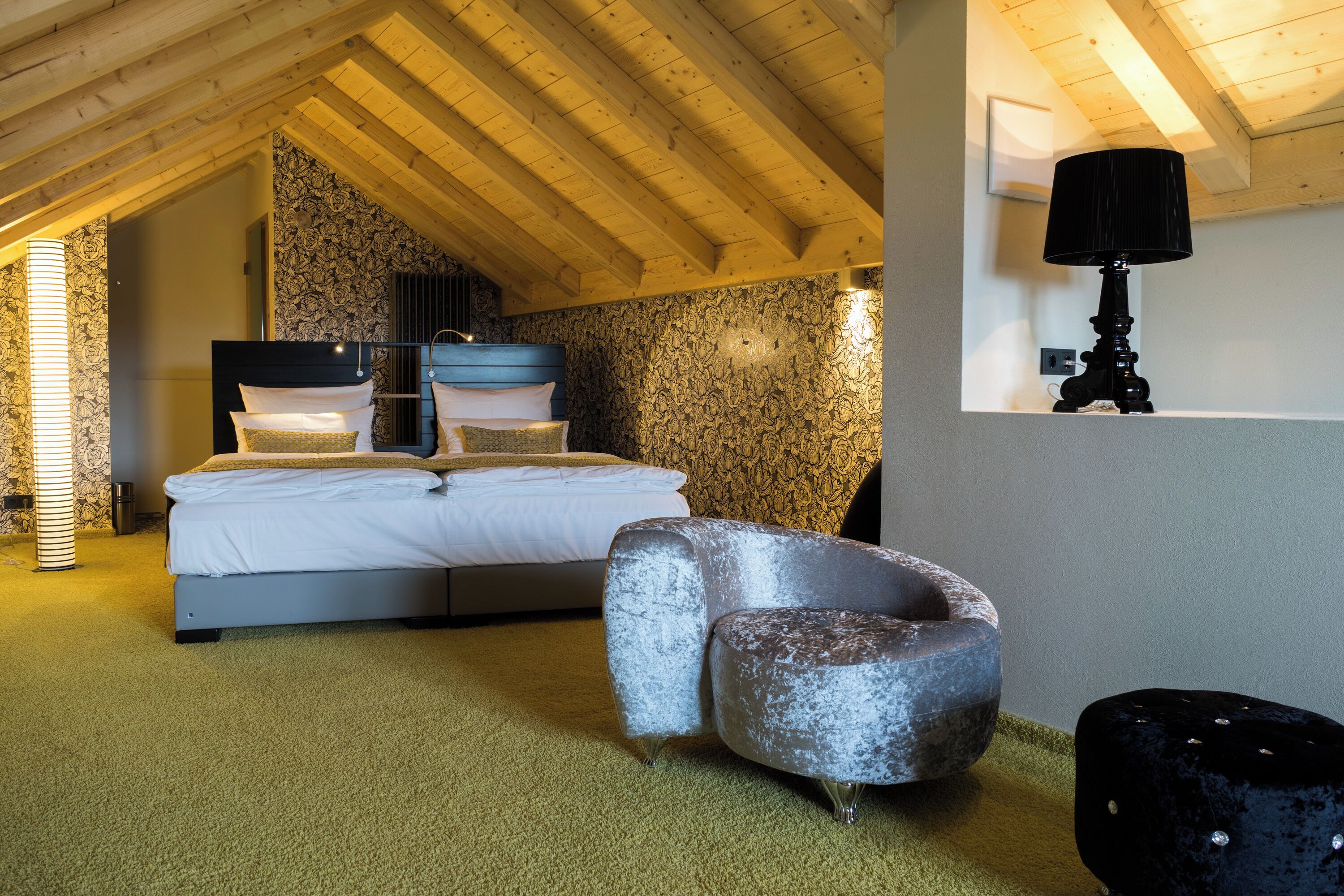 Quarto com cama, poltrona, abajur e parede texturizada.