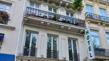 Fachada de hotel com estilo arquitetônico clássico, apresentando várias varandas com grades de ferro forjado, janelas amplas e um letreiro chamativo com a palavra 'HOTEL'.