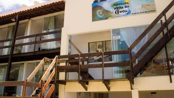 Um edifício com escadaria de madeira, várias janelas e uma placa que anuncia um destino de praia.