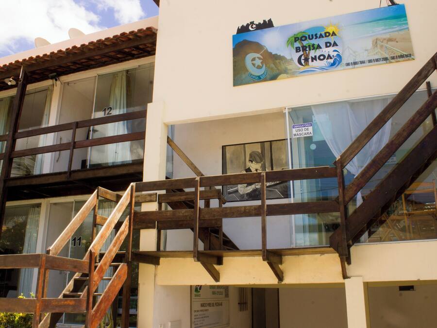 Um edifício com escadaria de madeira, várias janelas e uma placa que anuncia um destino de praia.