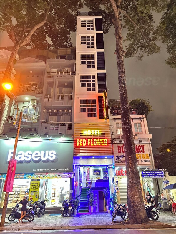 Um edifício de vários andares com um letreiro grande que diz 'HOTEL RED FLOWER'.