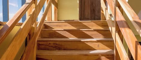 Uma escada de madeira com corrimão que leva a uma porta.