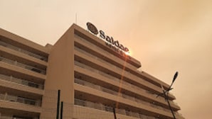 Um edifício de vários andares com uma placa grande no topo.