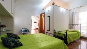 Quarto com duas camas, uma cadeira e uma escrivaninha.