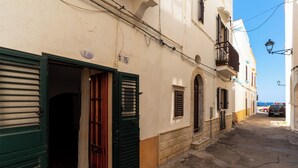 Uma rua estreita com edifícios com arquitetura tradicional, incluindo uma porta e portões de janela visíveis.