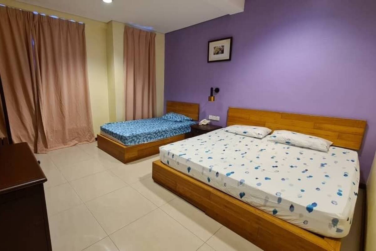 Quarto com duas camas, uma escrivaninha de madeira e um criado-mudo.