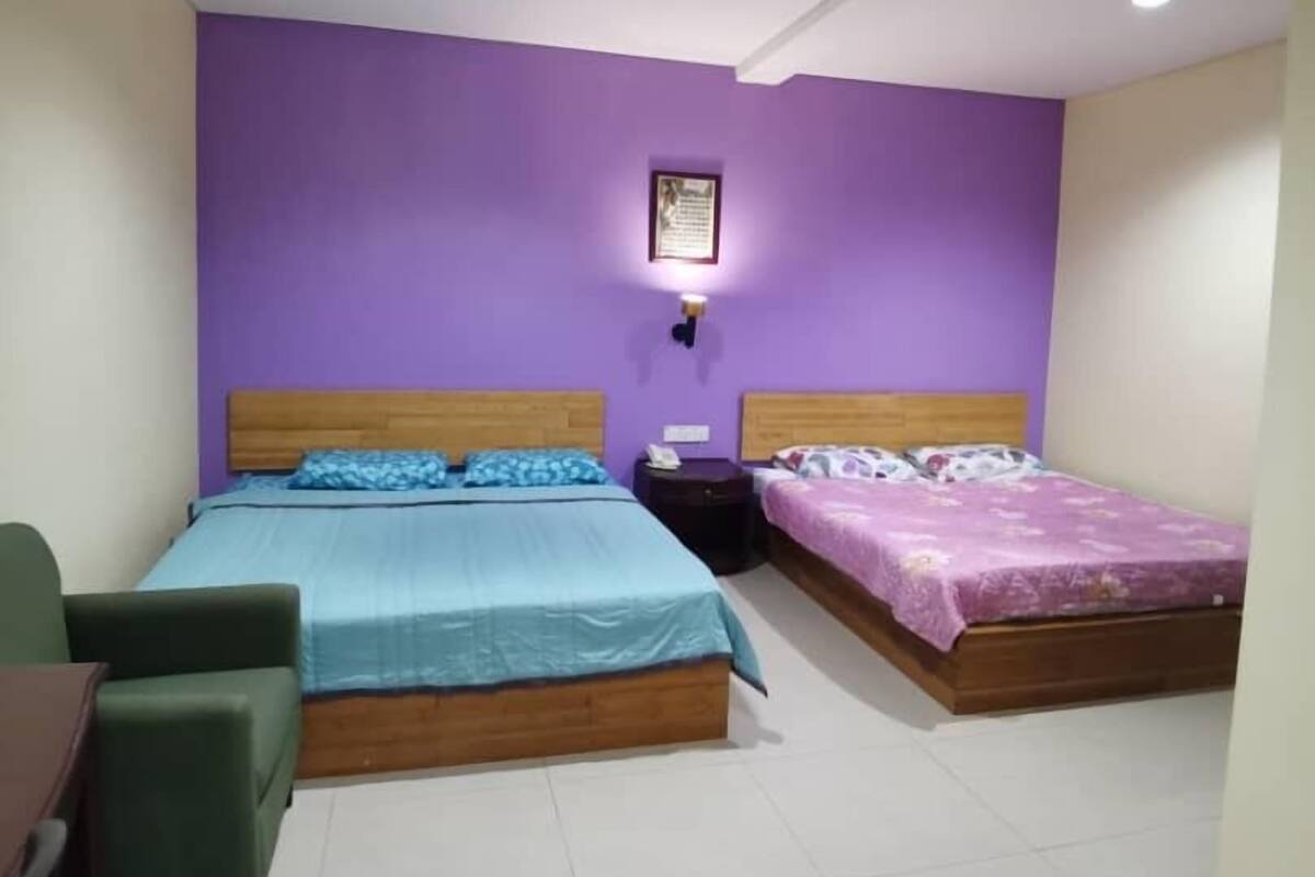 Quarto com duas camas, uma escrivaninha e uma cadeira.
