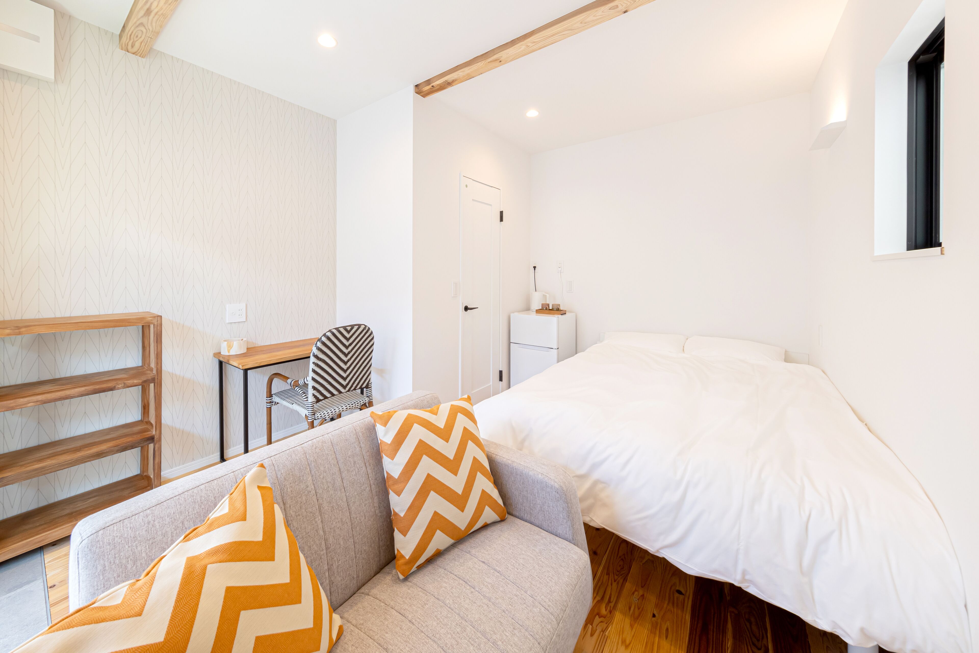 Um quarto moderno com cama, sofá e uma pequena mesa com cadeira.