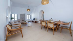 Uma sala de estar ampla com uma mesa de jantar, cadeiras de madeira e um sofá.