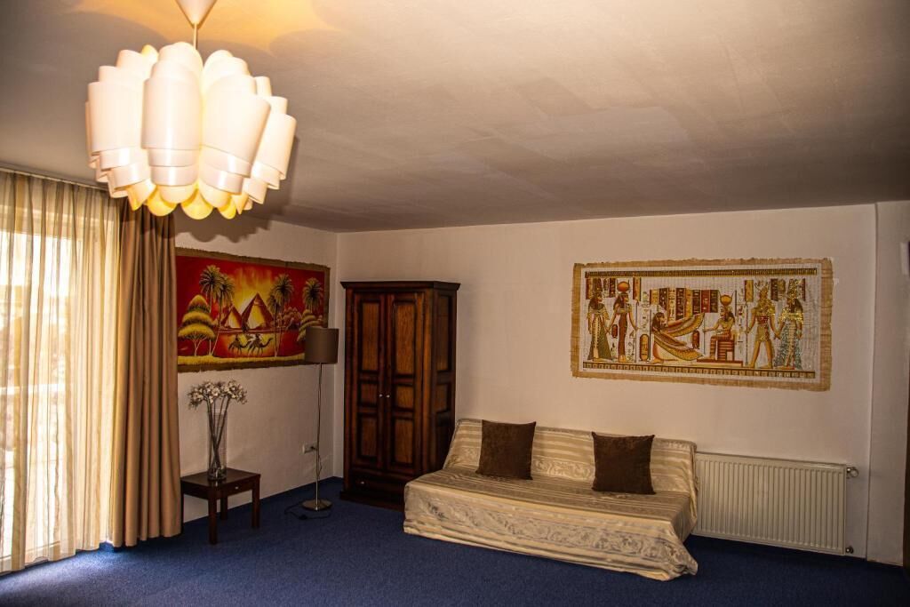 Quarto com cama, um lustre, um quadro, um armário e um radiador.