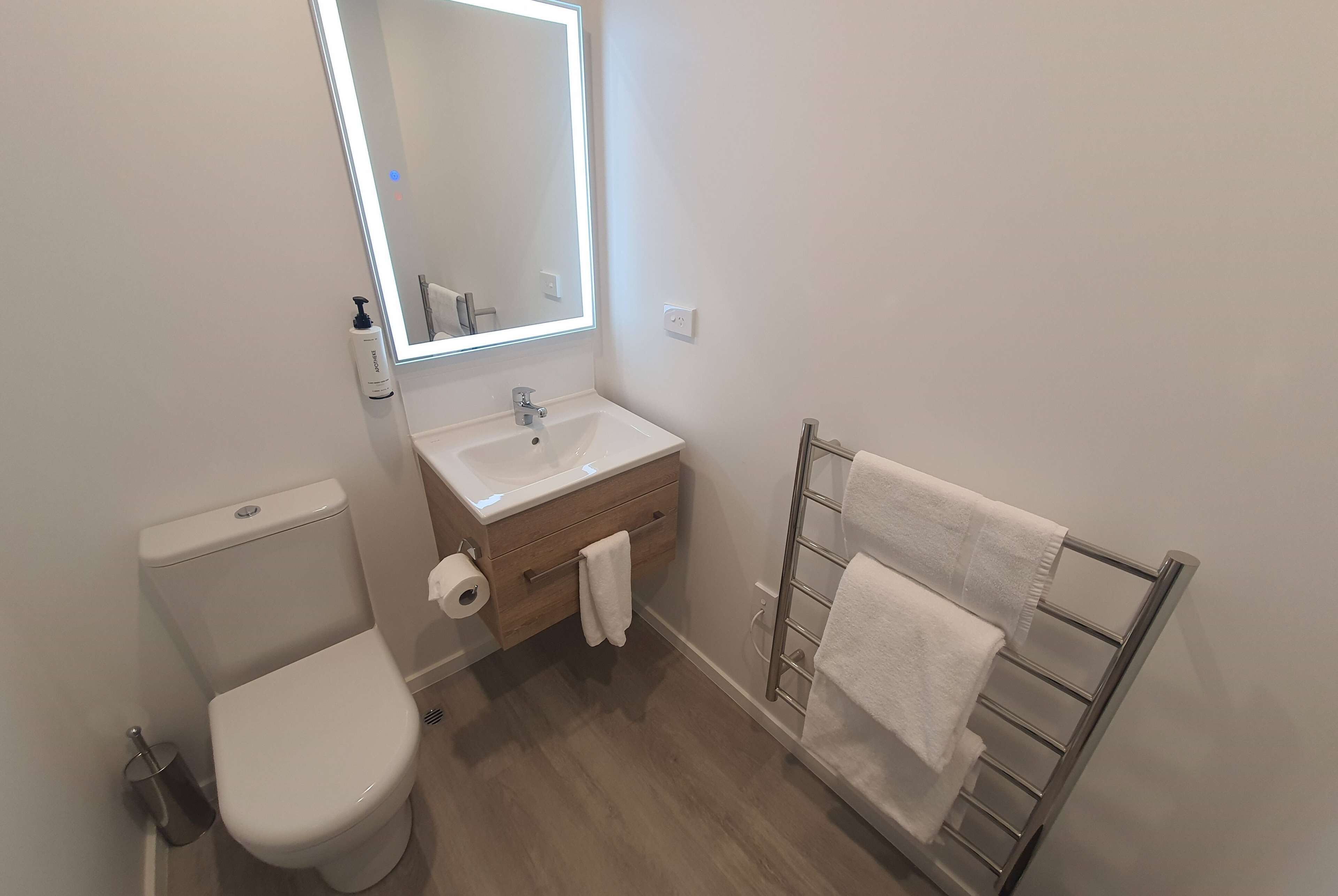 Uma casa de banho moderna com sanita, lavatório e porta-toalhas.
