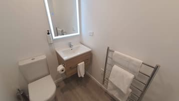 Uma casa de banho moderna com sanita, lavatório e porta-toalhas.