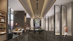 Um saguão moderno com área de estar central, um lustre e um balcão de recepção.