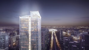 Um edifício alto com fachada de vidro moderna, cercado por outros edifícios imponentes em uma paisagem urbana.
