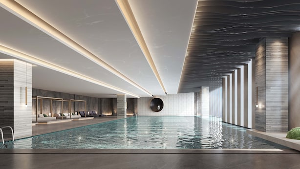 Piscina interior moderna com design elegante, apresentando uma piscina longa e estreita, área de estar central com espreguiçadeiras e teto contemporâneo com iluminação linear.