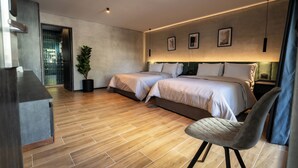 Quarto de hotel moderno com duas camas, uma escrivaninha, uma cadeira e um vaso de planta.