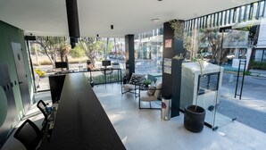 Um espaço de escritório moderno com um balcão comprido, cadeiras e uma grande janela com vista para a rua.