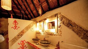 Casa de banho com lavatório de pedra, espelho e porta-toalhas.
