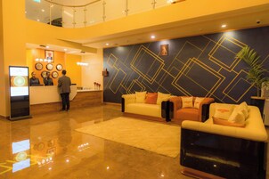 Um hall de entrada com uma mesa de recepção, um sofá e uma parede grande com padrões geométricos.