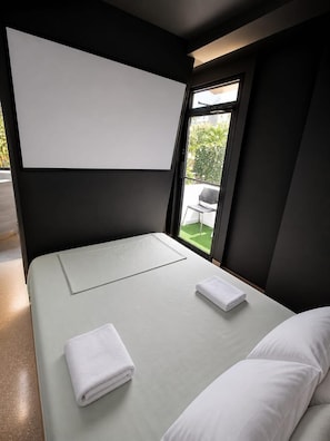 Quarto de hotel moderno com cama, uma janela grande e vista para o exterior.