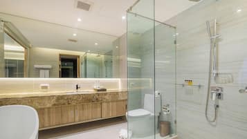 Casa de banho moderna com chuveiro envidraçado, banheira independente e toucador com bancada de mármore.
