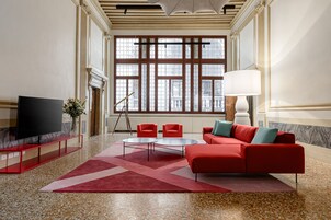 Uma sala de estar moderna com um sofá vermelho, duas poltronas vermelhas, uma mesa de centro, uma televisão e uma grande janela com vista.