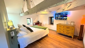 Quarto com cama, penteadeira, televisão fixada na parede e janela.