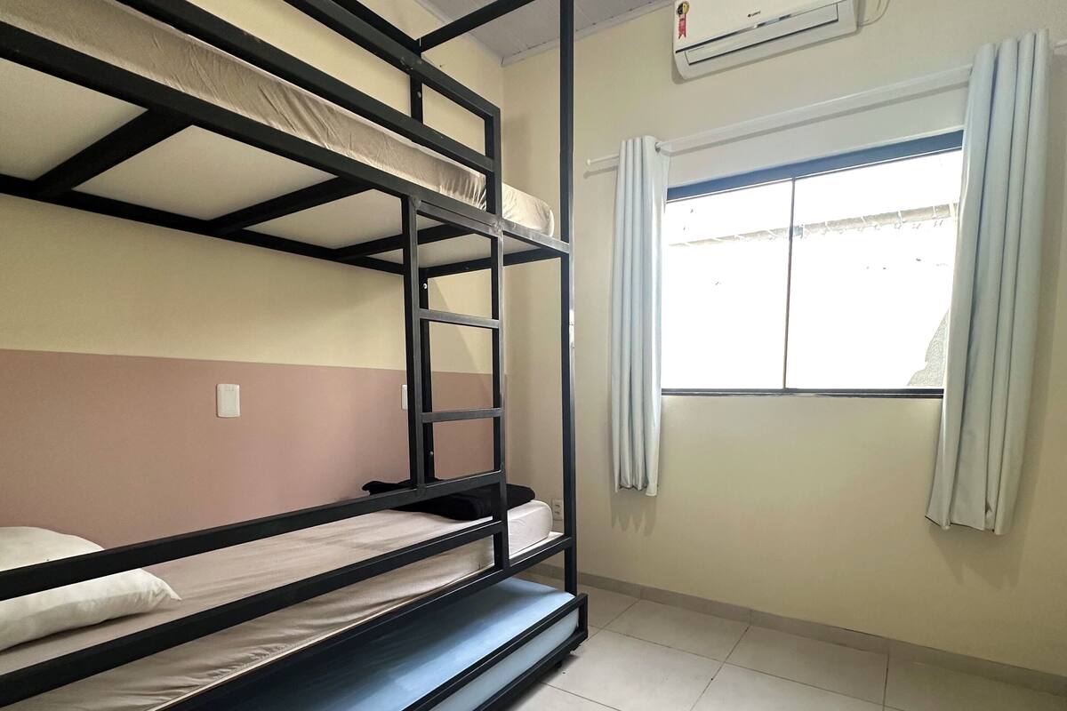 Quarto com beliche, janela e ar condicionado.