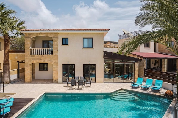 Um edifício de dois andares com piscina, área de estar ao ar livre e um pátio coberto.