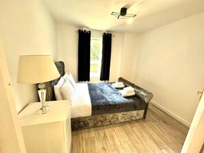 Um quarto pequeno e acolhedor com uma cama de solteiro, abajur e janela com cortinas.