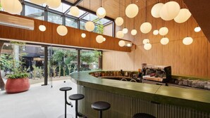 Uma área de bar moderna com balcão curvo, vários bancos e iluminação pendente.