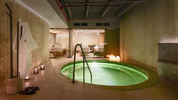 Uma área de spa com piscina, espaço para chuveiros e um balcão de recepção.