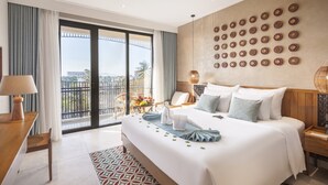 A hotel room with a large bed, a desk, a chair, a balcony with a view, and a wall decorated with circular patterns.