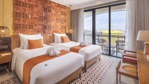 A hotel room with two beds, a balcony with a view, and a dining area with chairs.