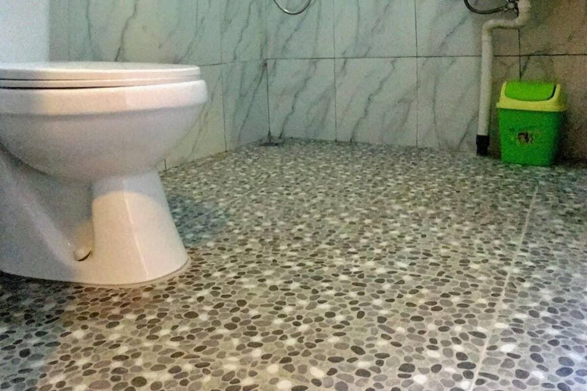 Casa de banho com sanita, chuveiro e lavatório.