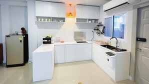 Uma cozinha compacta com armários brancos, forno embutido, pia e janela com vista.