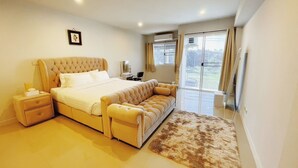 Quarto moderno com uma cama grande, um sofá, uma mesa de cabeceira e vista para o exterior através de uma porta de correr.