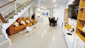 Um apartamento moderno com escada, sala de estar, área de jantar, cozinha e TV fixada na parede.