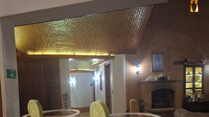 Dois copos de martini com gomos de limão sobre uma mesa de madeira, uma lareira e uma sala de estar acolhedora com um tapete estampado.