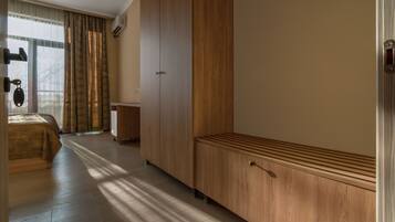 Quarto de hotel com um guarda-roupa grande, uma cama e um banco.